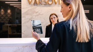 Bancada de recepção com parede de mármore e placa com a inscrição "VARSOVIA".
