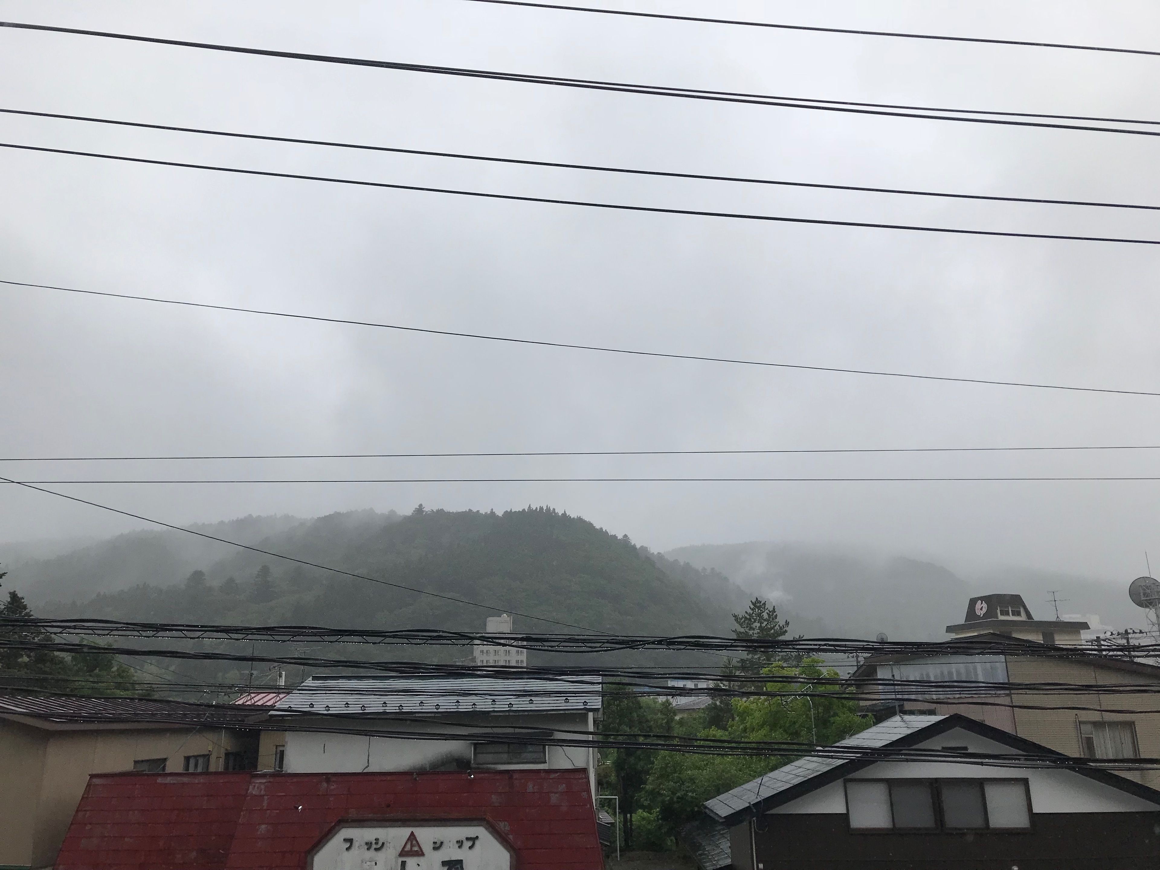 Zona residencial com casas, linhas de energia e uma montanha ao fundo.