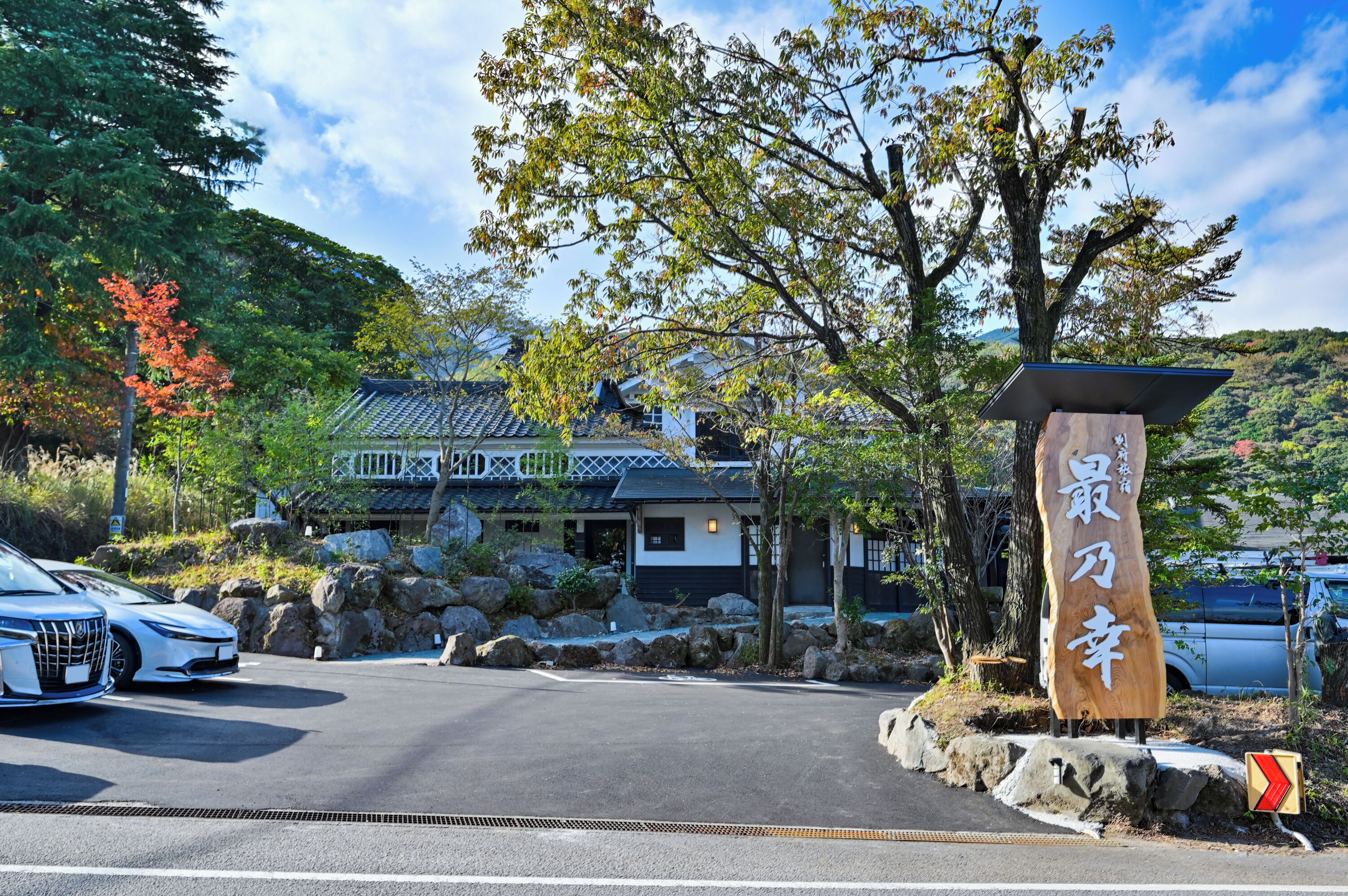 Um edifício japonês tradicional com telhado em telhas, rodeado por pedras e árvores.