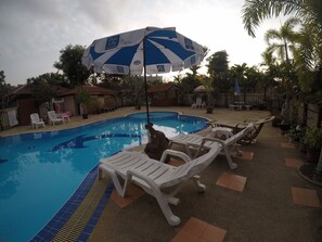 Piscina com espreguiçadeiras e guarda-sol.