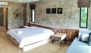 Quarto com cama grande, mesa de cabeceira, sofá e janela com vista.