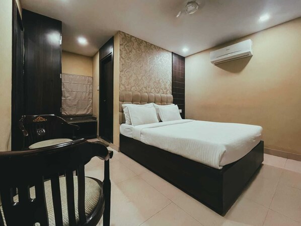 Quarto com cama, uma cadeira, guarda-roupa e ar condicionado.