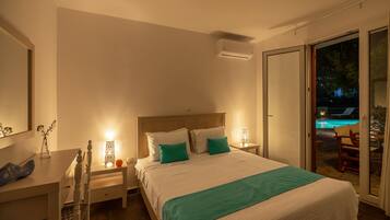 Quarto com cama, mesas de cabeceira, luminária e vista para uma piscina através de uma porta de correr.
