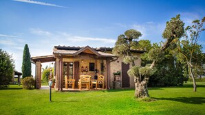 Uma casa rústica com varanda, móveis de madeira e um gramado bem cuidado.