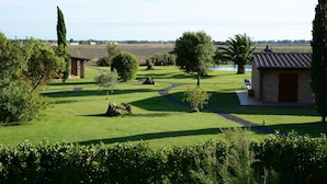 Um jardim bem cuidado com um caminho, um pequeno edifício e uma vista distante de campos.