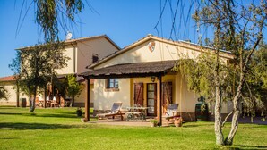 Um edifício de dois andares com um pátio, área de estar externa e um pérgola.