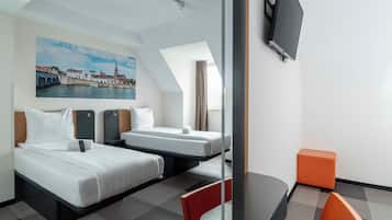 Quarto de hotel com duas camas, uma televisão, um quadro de uma paisagem urbana, chão xadrez e um banquinho laranja.