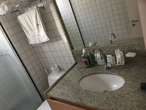 Casa de banho com uma pia branca, um espelho e uma toalha pendurada num suporte.