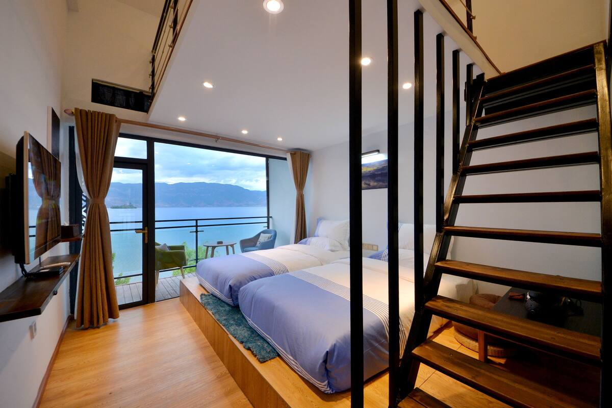 Quarto moderno com uma grande janela, uma cama, uma TV e uma escada.