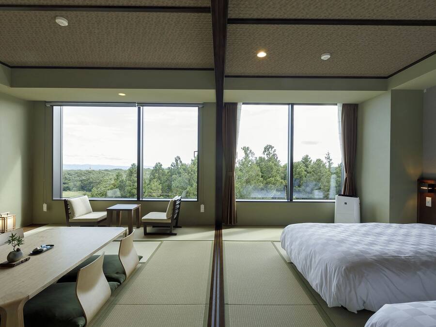 Quarto de hotel com cama, escrivaninha e vista para o exterior.