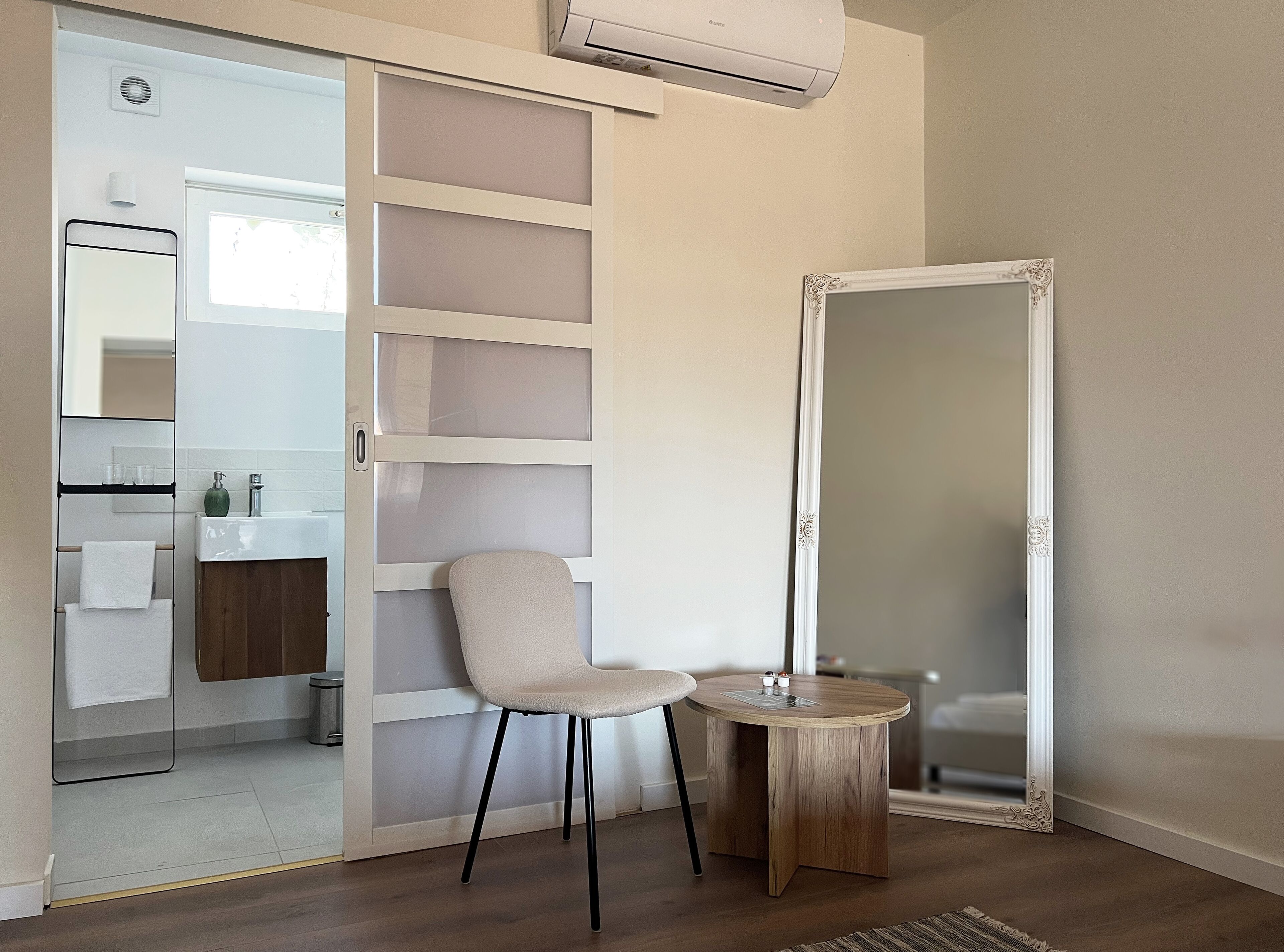 Casa de banho moderna com toucador branco, espelho e porta-toalhas.