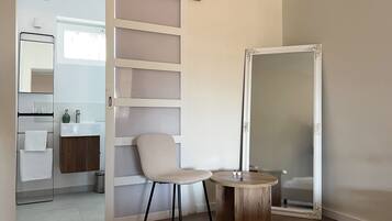 Casa de banho moderna com toucador branco, espelho e porta-toalhas.