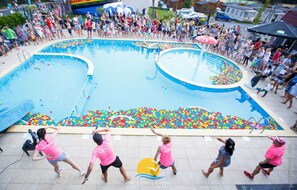Uma piscina cercada por um grupo de pessoas, com uma piscina de bolinhas cheia de bolas coloridas.