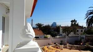 Uma varanda com uma escultura branca, um pátio com azulejos e vista para um edifício com cúpula azul.