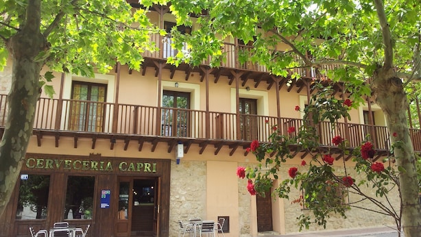Um edifício com uma placa que diz "Cerveceria Capri" e mesas ao ar livre.