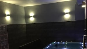 Um quarto com iluminação suave, uma banheira de hidromassagem, um lance de escadas e luminárias fixadas na parede.