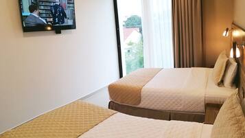 Quarto de hotel com duas camas, uma televisão na parede e uma janela com cortinas.