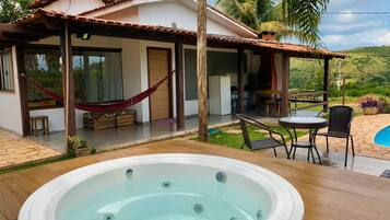 Uma casa com varanda, banheira de hidromassagem e vista para as colinas.