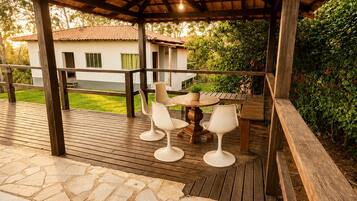 Uma área externa coberta com deck de madeira, piso de pedra e piscina.