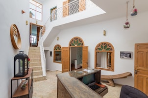 Um interior espaçoso com escadas, portas de madeira e um balcão de recepção.