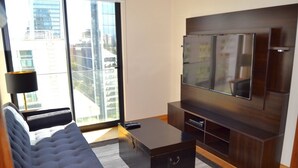 Uma sala de estar moderna com um sofá, uma mesa de centro, uma televisão e uma janela grande com vista para a cidade.