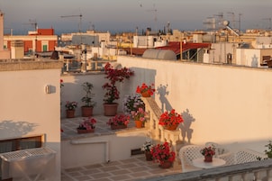 Terraço no telhado com vasos de plantas e uma mesa pequena.