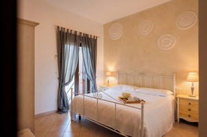 Quarto com cama, mesas de cabeceira e cortinas.