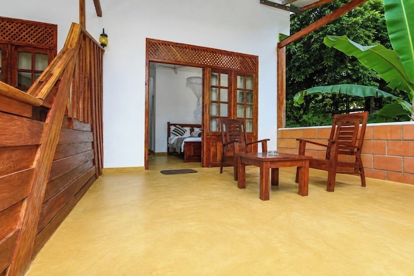 Escada de madeira que leva a um quarto com uma cama, uma mesa de madeira e cadeiras.