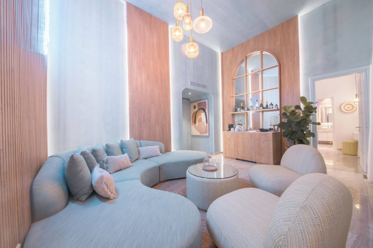 Uma sala de estar moderna com um sofá modular curvo, mesa de centro redonda e iluminação pendente.