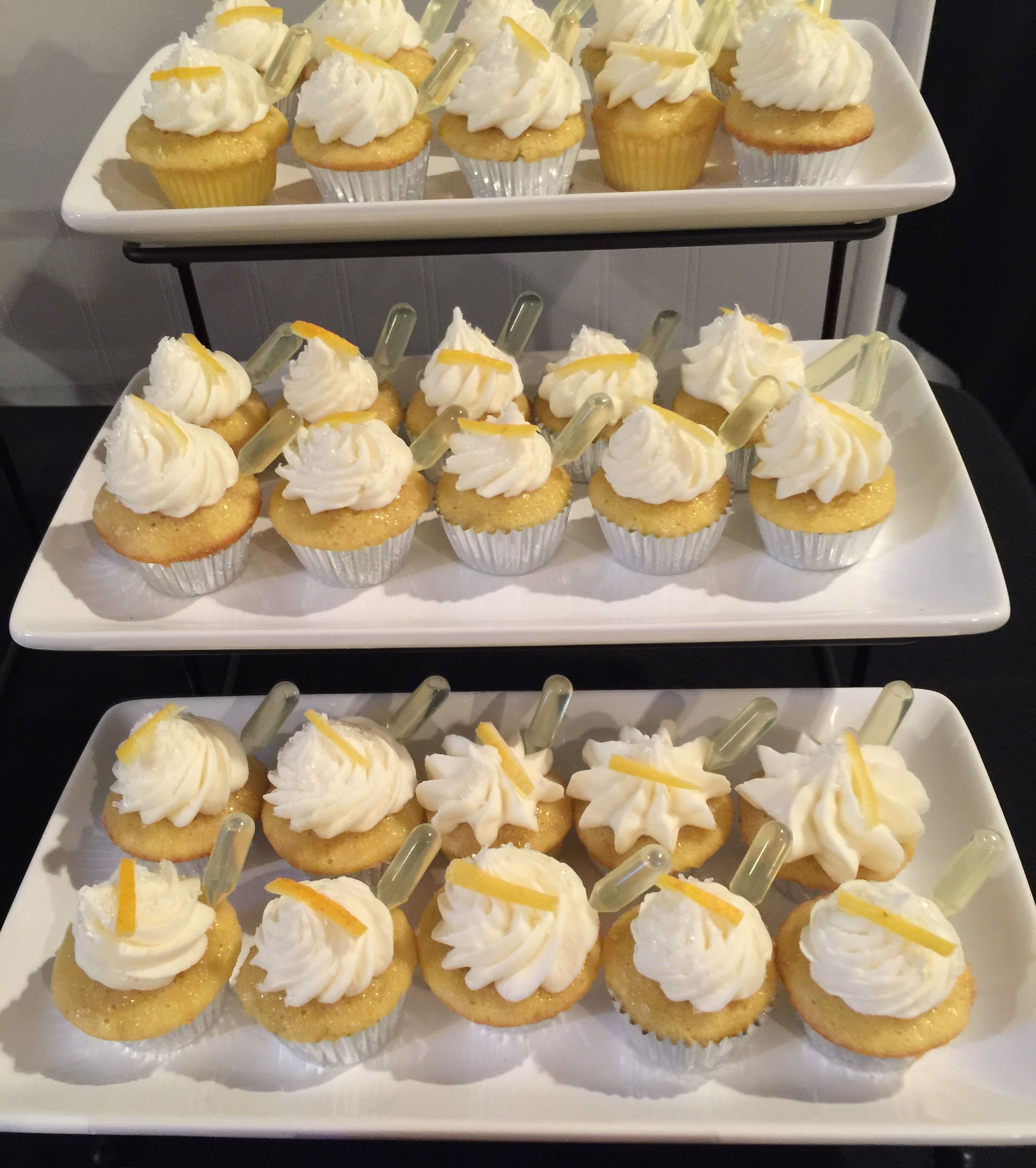 Uma bandeja de cupcakes com cobertura branca e fatias de limão em palitos.