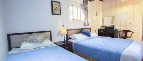 Quarto de hotel com duas camas, uma escrivaninha, uma cadeira e um espelho.