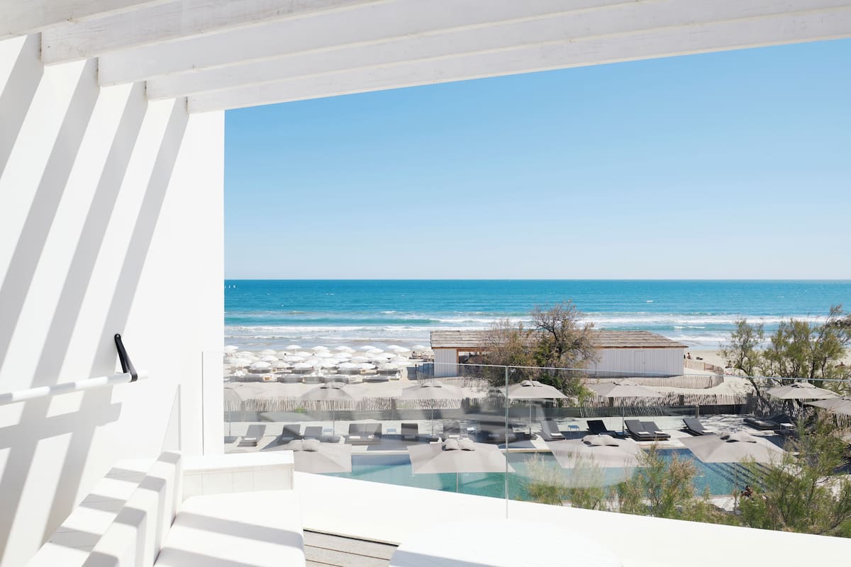 Vista da piscina com guarda-sóis e espreguiçadeiras, com vista para o oceano.