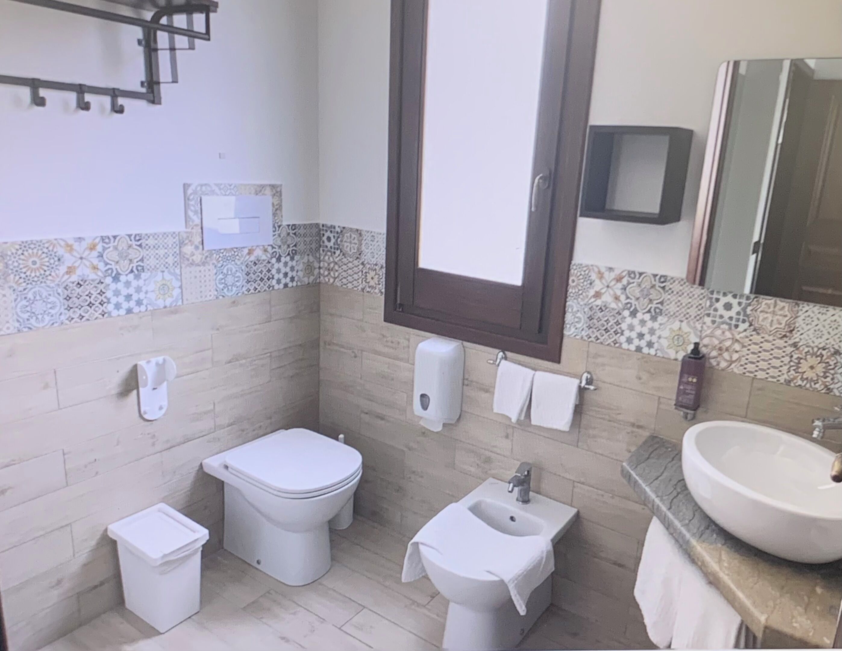 Casa de banho com sanita, bidé, lavatório e espelho.