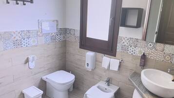 Casa de banho com sanita, bidé, lavatório e espelho.