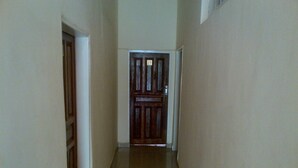 Um corredor estreito com uma porta de madeira no final.