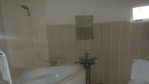 Um banheiro com banheira, pia de vidro e vaso sanitário.