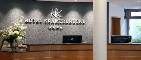 Uma receção com design moderno, exibindo o logotipo e o nome do hotel.