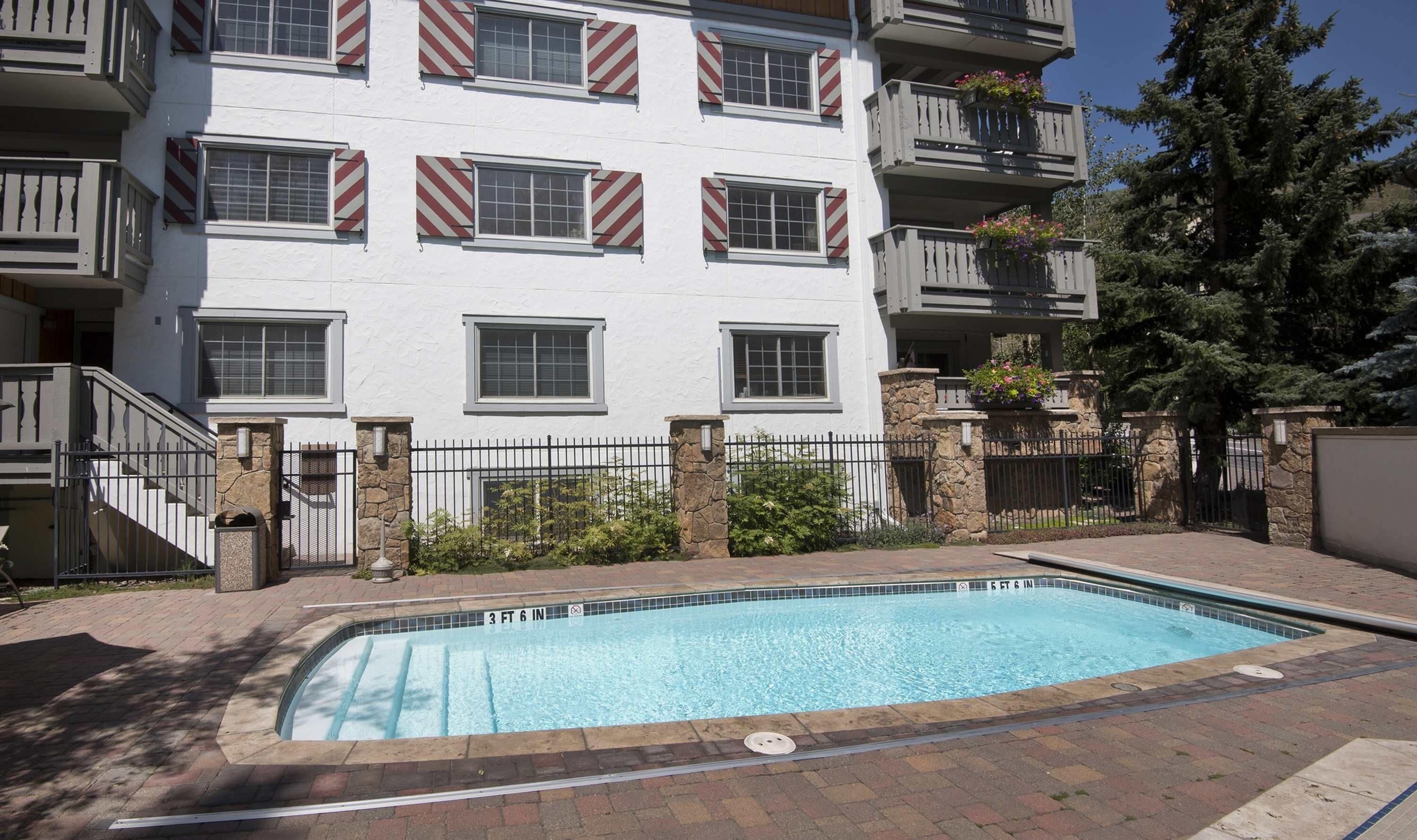 Um edifício residencial com piscina, pilares de pedra e cerca de pedra.
