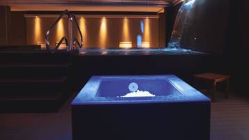 Uma área de spa com hidromassagem, uma cascata e uma banheira de pedra aquecida.