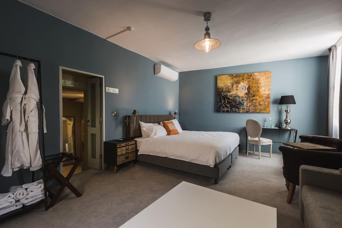 Quarto com cama, cadeira, mesa e um quadro na parede.
