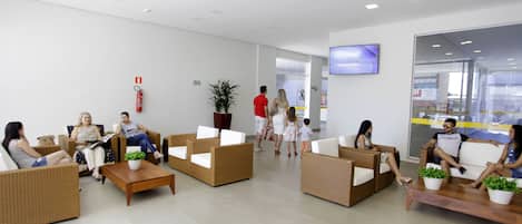 Um lobby moderno com mobiliário de vime, televisão de tela plana e entrada de vidro.