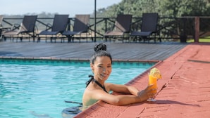 Uma área junto à piscina com espreguiçadeiras e guarda-sóis.