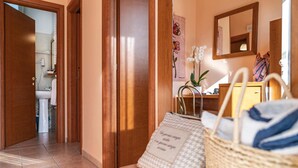 Um banheiro de hotel com porta de madeira, porta-toalhas, espelho e um dispensador de toalhas fixado na parede.