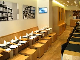 Um restaurante com várias mesas de jantar, cada uma posta com pratos, copos e talheres.