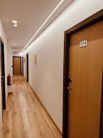 Um corredor de hotel com soalho de madeira, um extintor de incêndio e portas com os números 504 e 507.