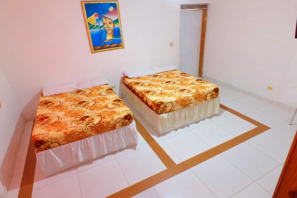 Quarto com duas camas, uma porta e um quadro fixado na parede.