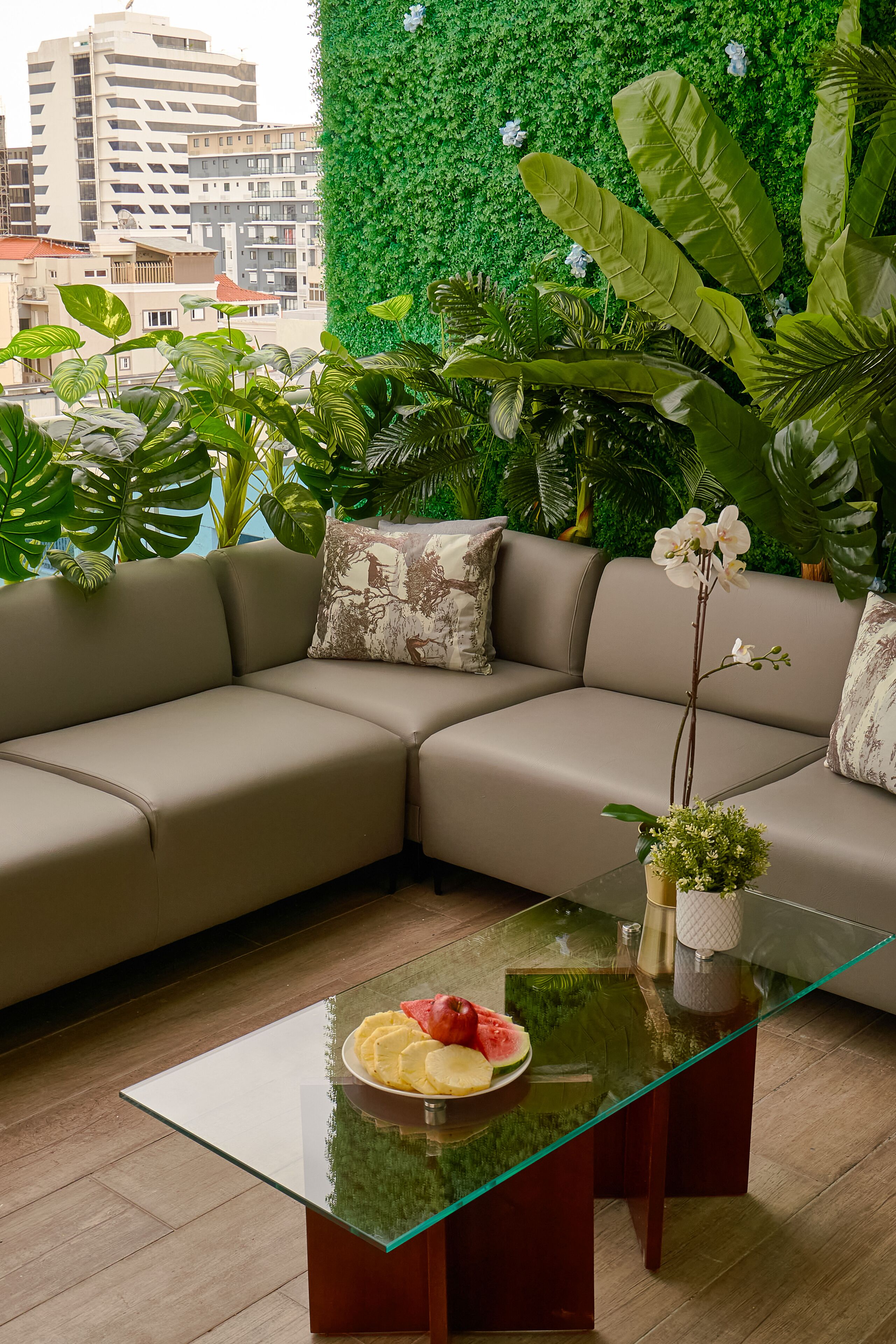 Uma sala de estar moderna com uma mesa de centro de vidro, um sofá bege e plantas verdes exuberantes.