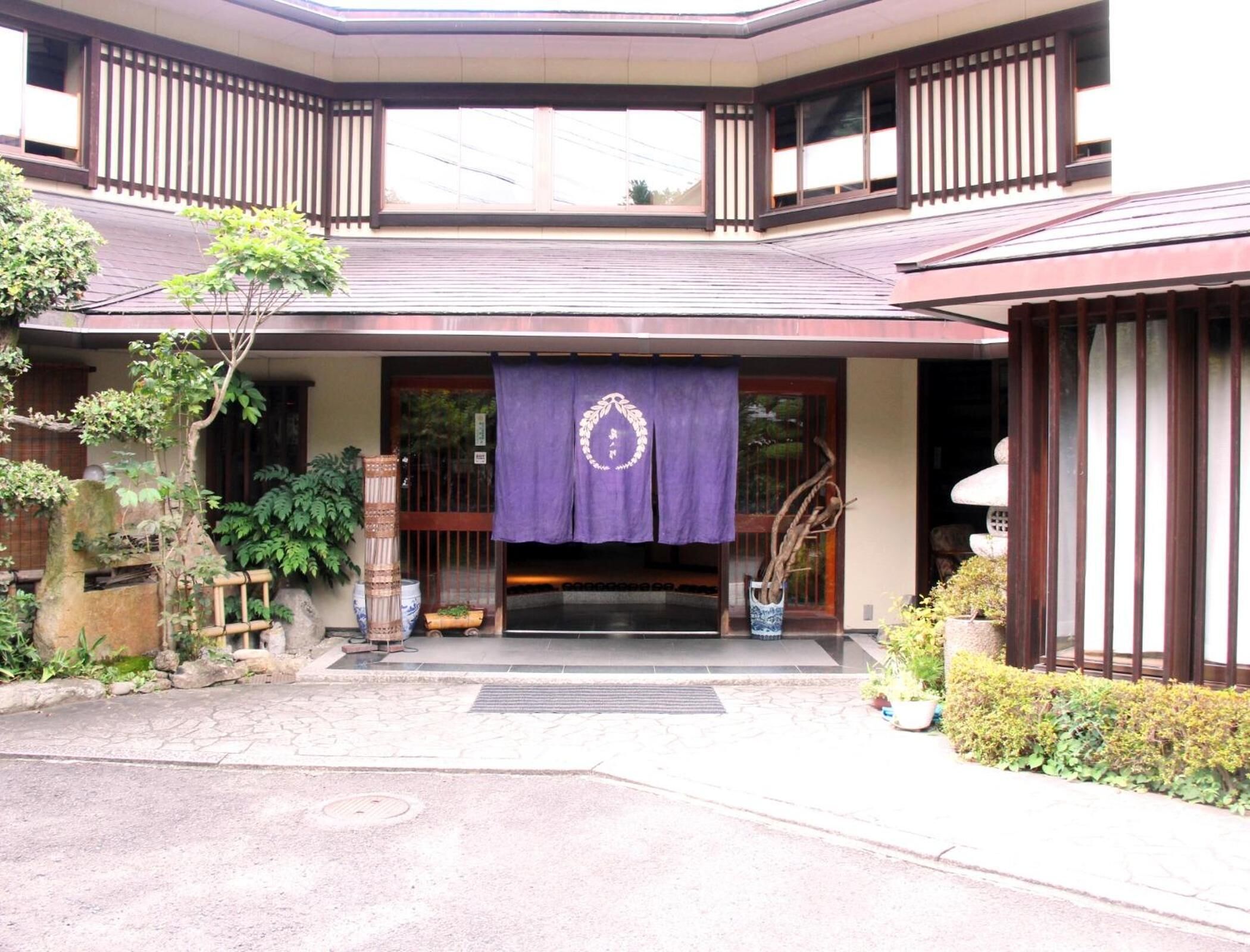 Um edifício japonês tradicional com fachada de madeira, entrada em telhas e um tecido roxo com um emblema circular.