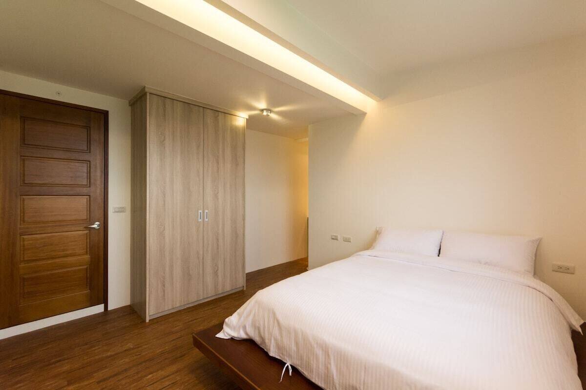 Quarto com cama, guarda-roupa de madeira e uma porta.