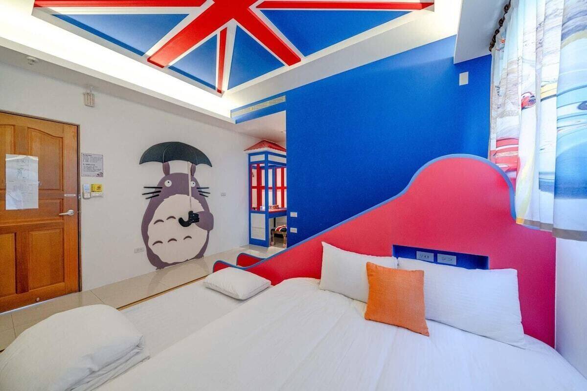 Quarto com cama, almofadas, um mural na parede e teto com design da bandeira do Reino Unido.